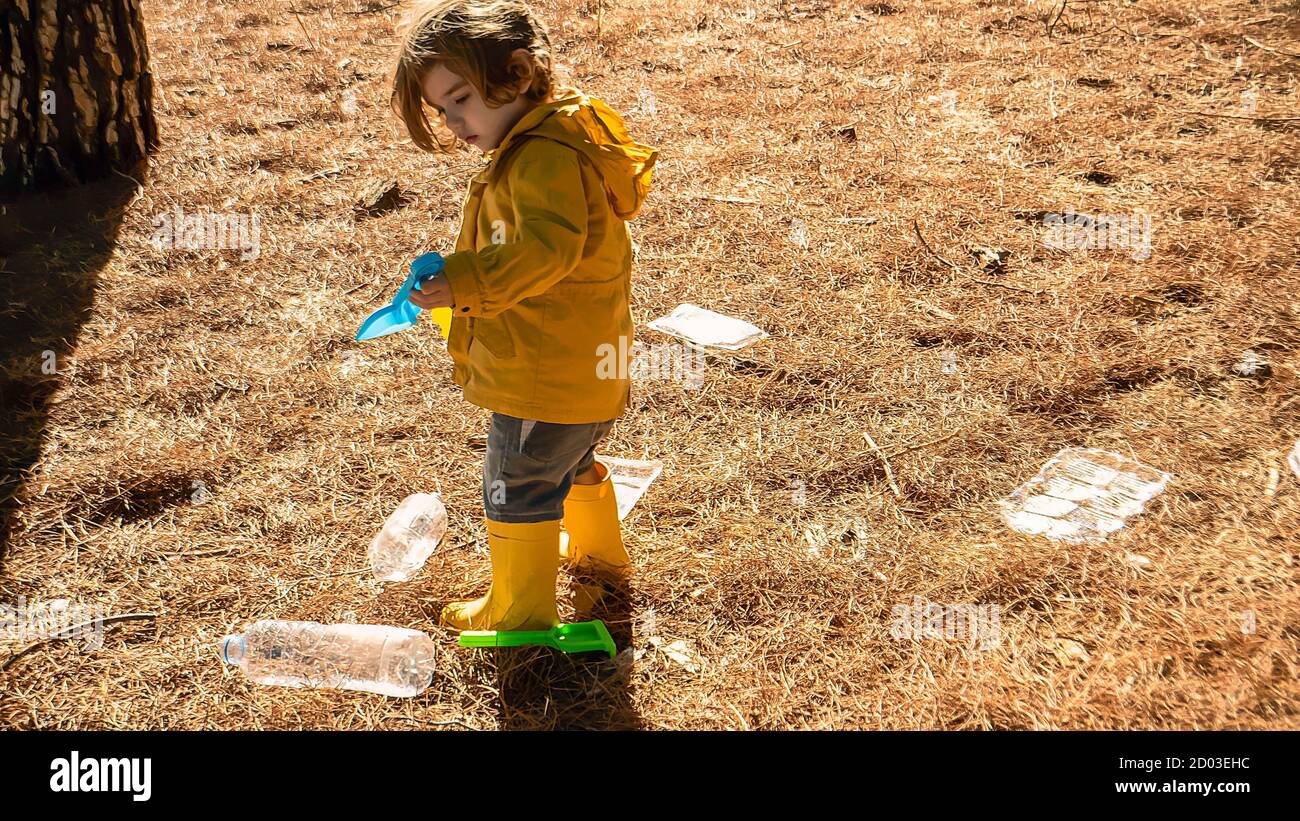 Young child is picking up plastic waste in the forest as a volunteer ...