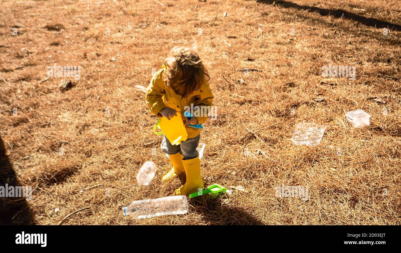 Young child is picking up plastic waste in the forest as a volunteer ...