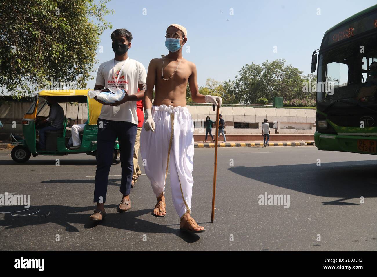 A volunteer dressed up as Mahatma Gandhi wearing a face mask as a ...