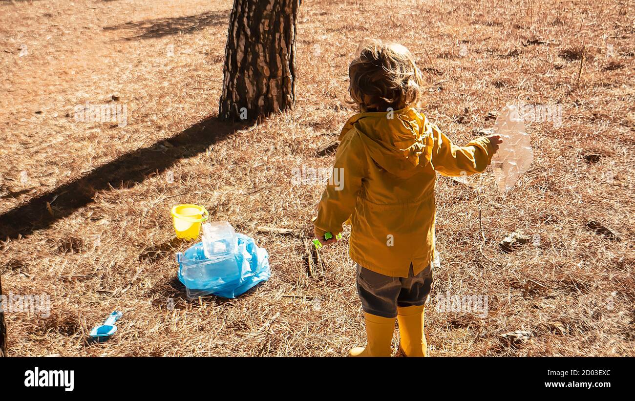 Young child is picking up plastic waste in the forest as a volunteer ...