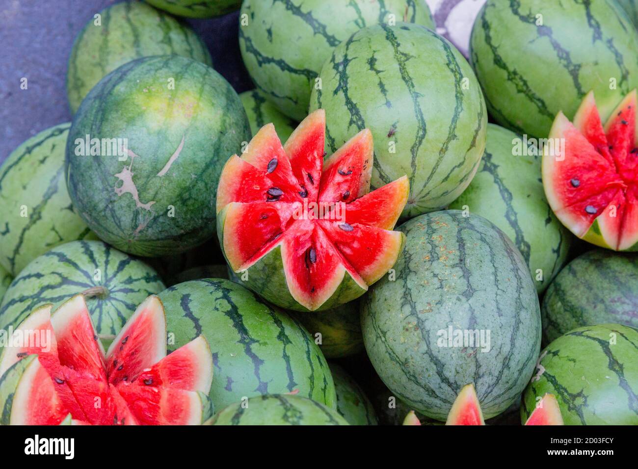Watermelon on display for sale at outdoor market with some cut open ...