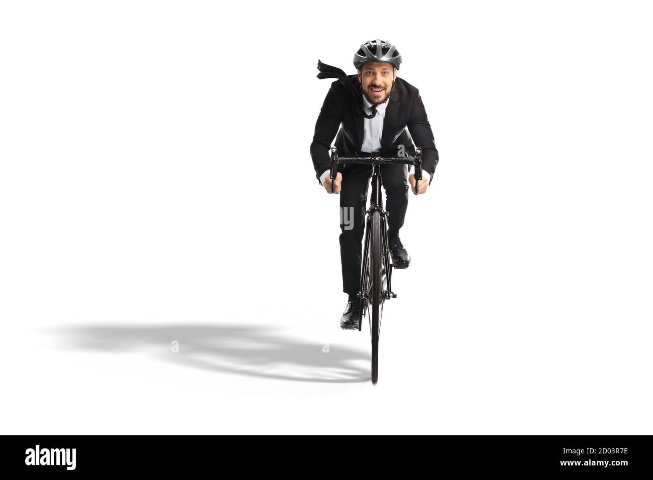 Young businessman in a suit riding a bicycle towards the camera ...