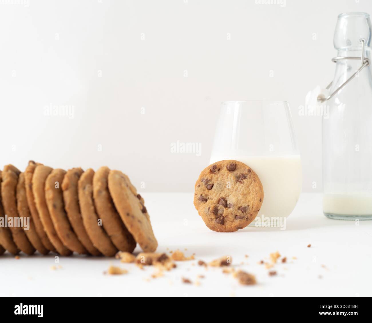 Selective focus of a chocolate chip cookie leaning on a glass of milk ...