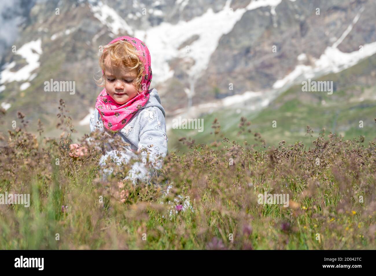 Cute blonde girl wearing pink scarf surrounded with spectacular alpine ...