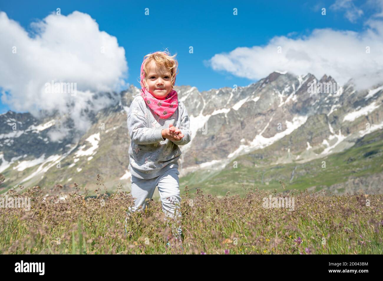 Cute blonde girl wearing pink scarf surrounded with spectacular alpine ...