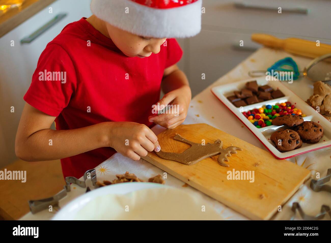A boy in a santa hat prepares cookies in the kitchen. Form for ...