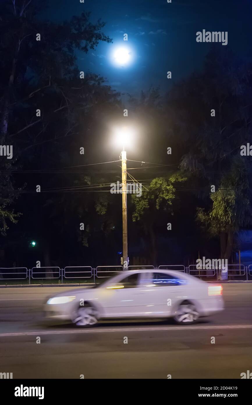 night landscape with moon and traveling car illuminated by flashlight ...