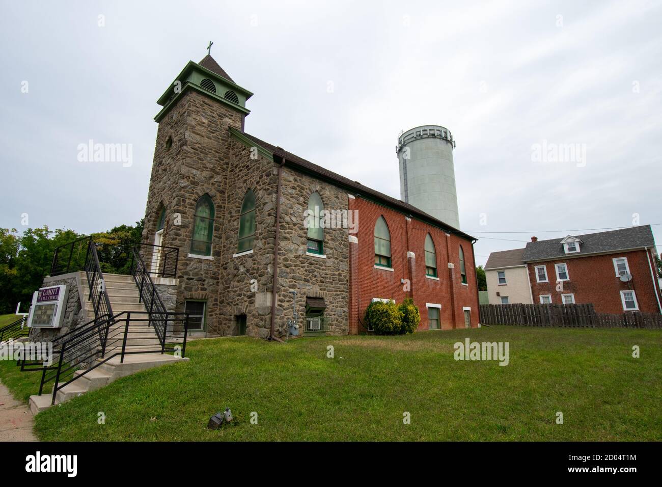 A Small Cobblestone Church With a Water Tower Behind it In Suburban ...