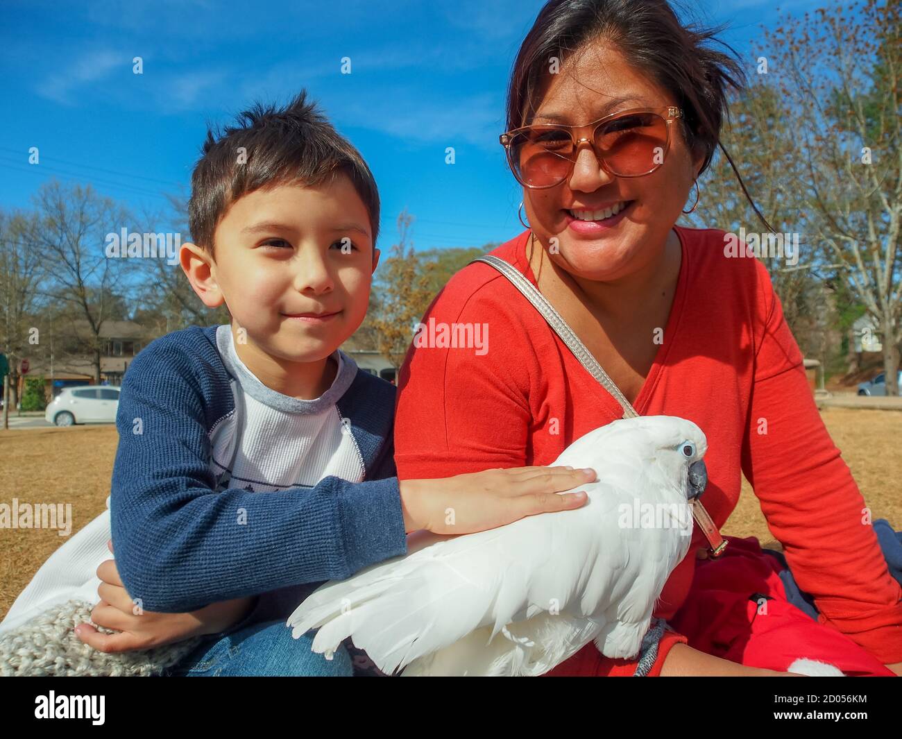 A woman and her young son holding and petting a white cockatoo Stock ...