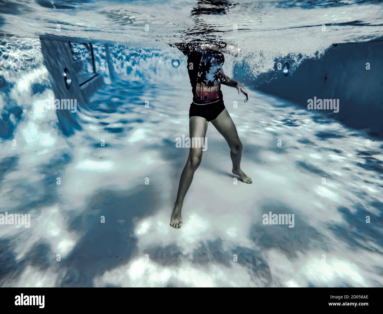 Teenage girl underwater running with light refracting off the sides of ...