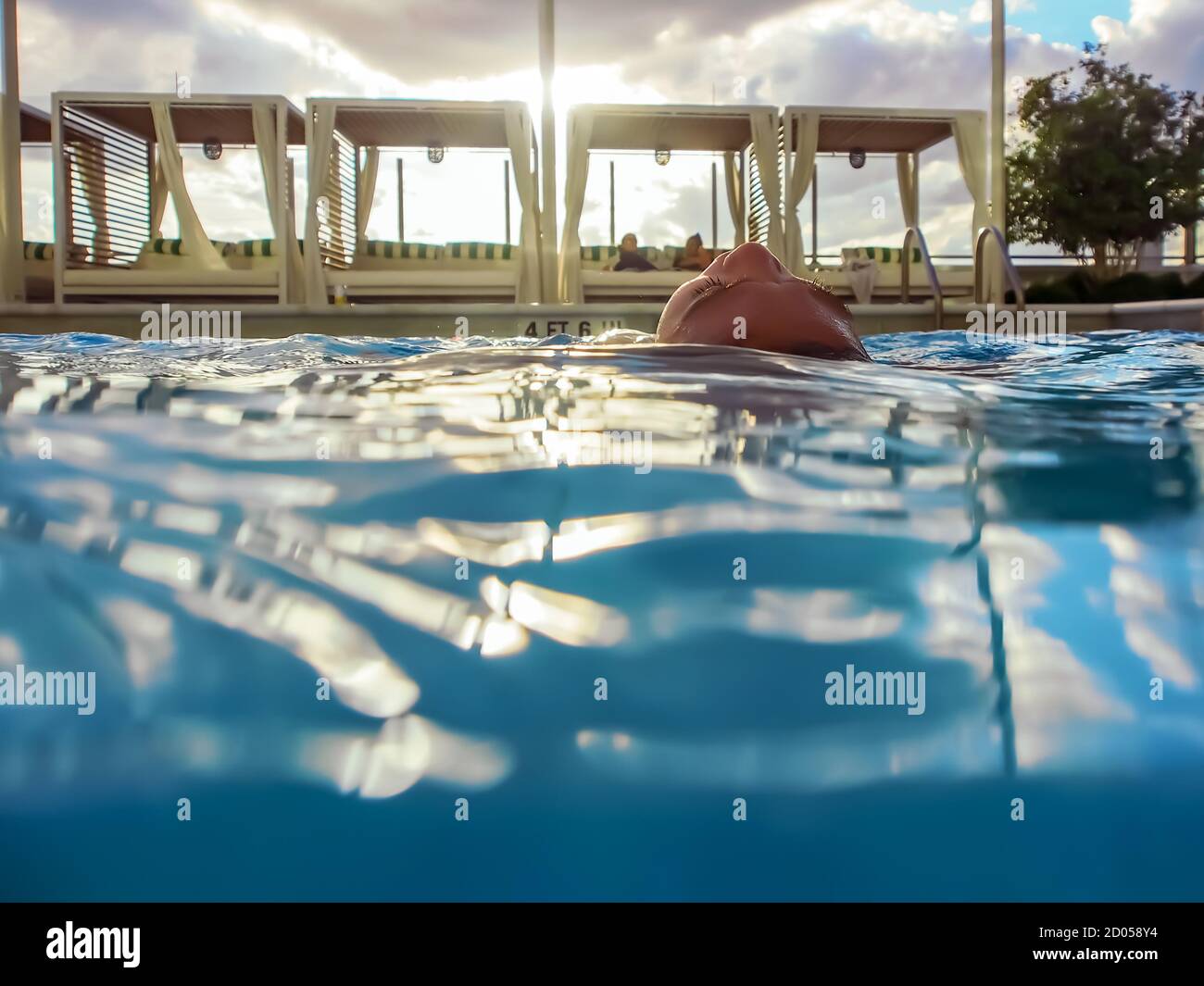 View of a pool's surface with a girl's head visible as she floats in ...