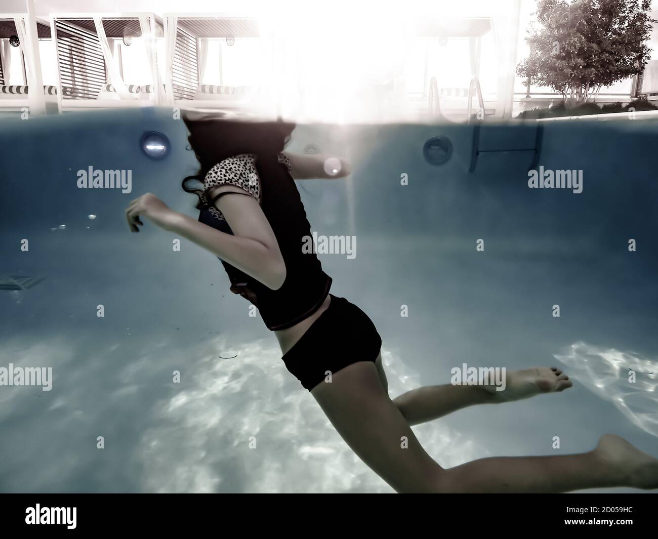 Split Shot Of Girl Floating Underwater And The Poolside Cabanas Above