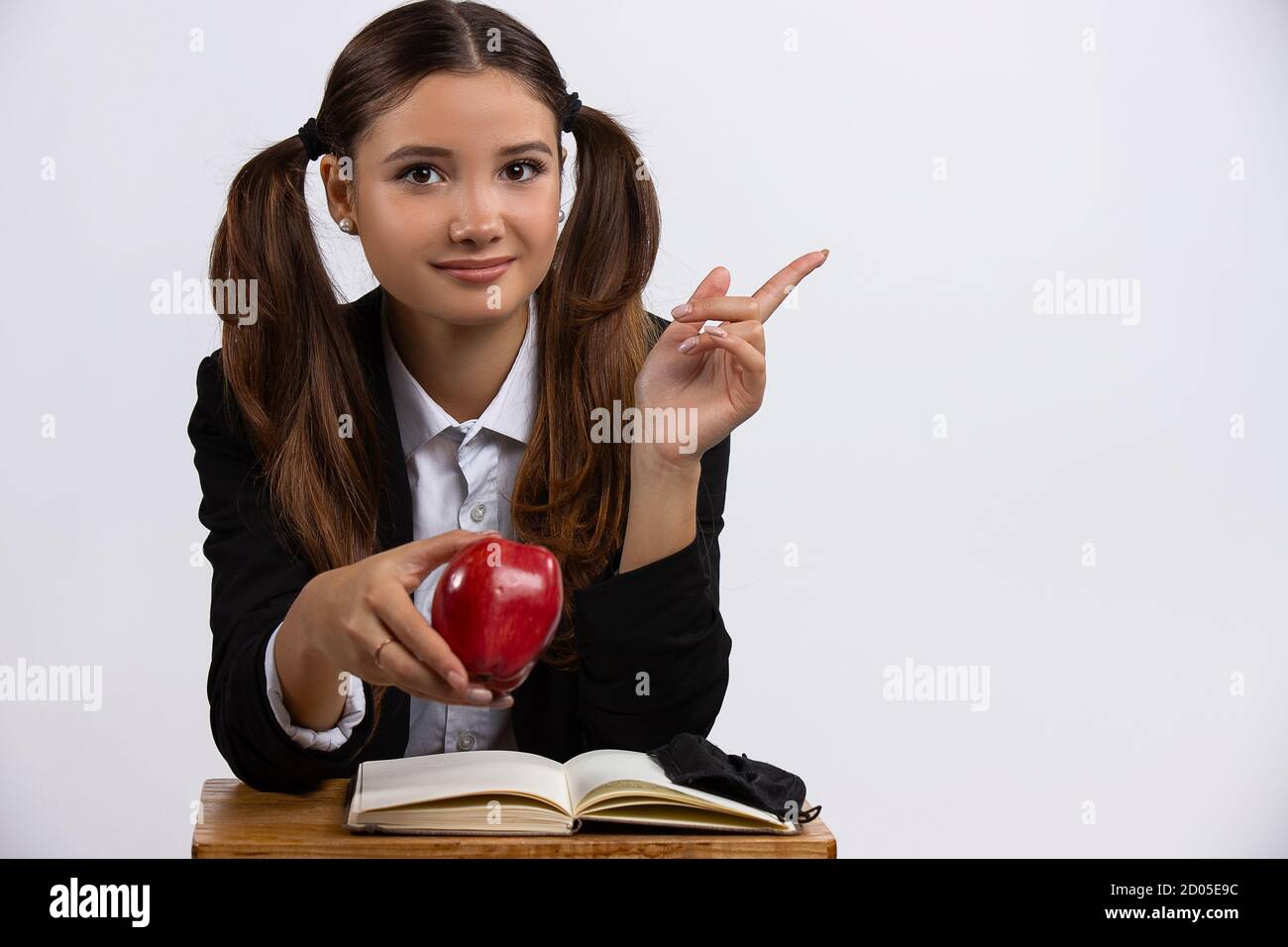 Portrait of pretty smiling girl sitting at the table pointing hands ...