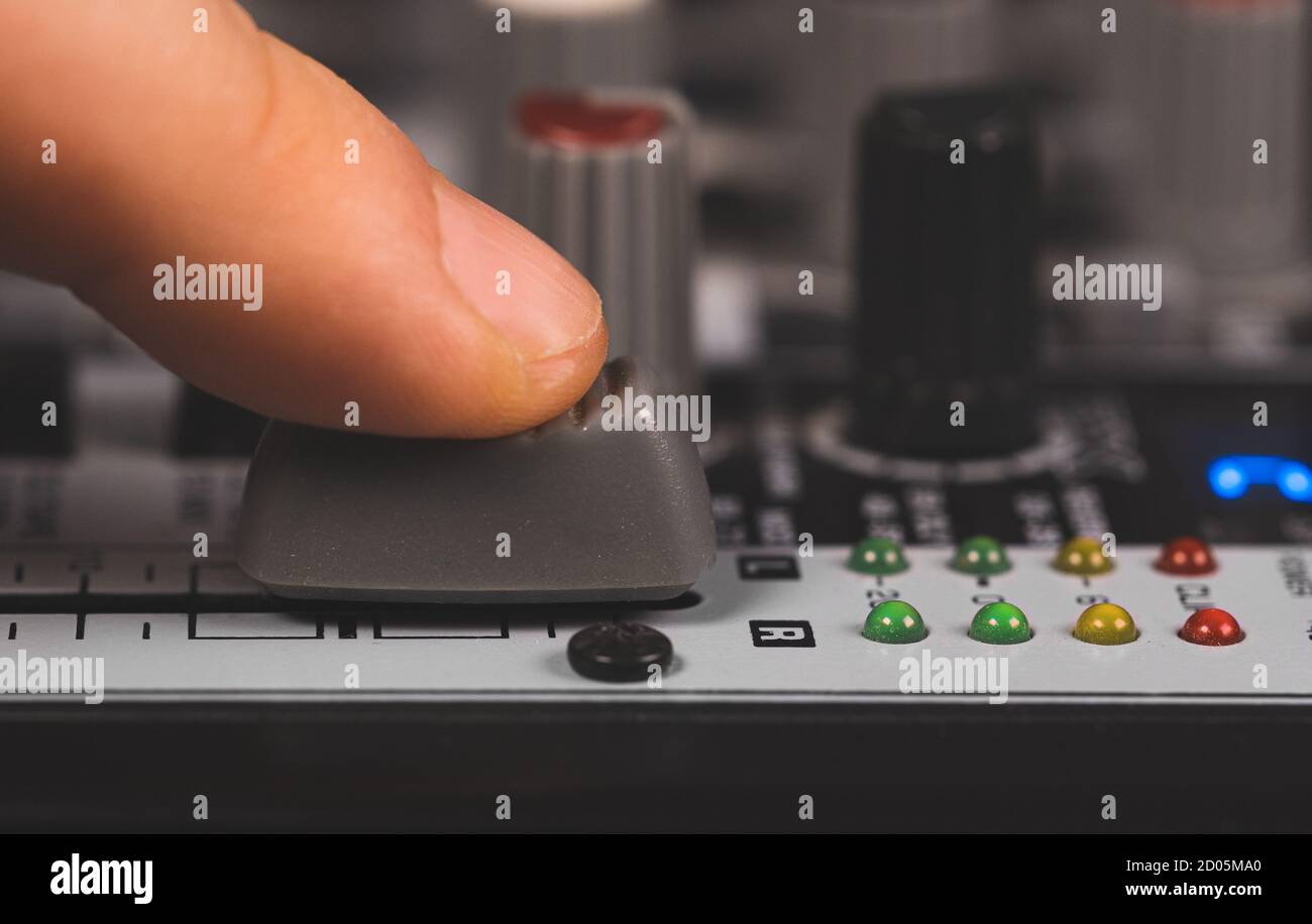 Sound engineer using main control fader of studio mixer Stock Photo - Alamy