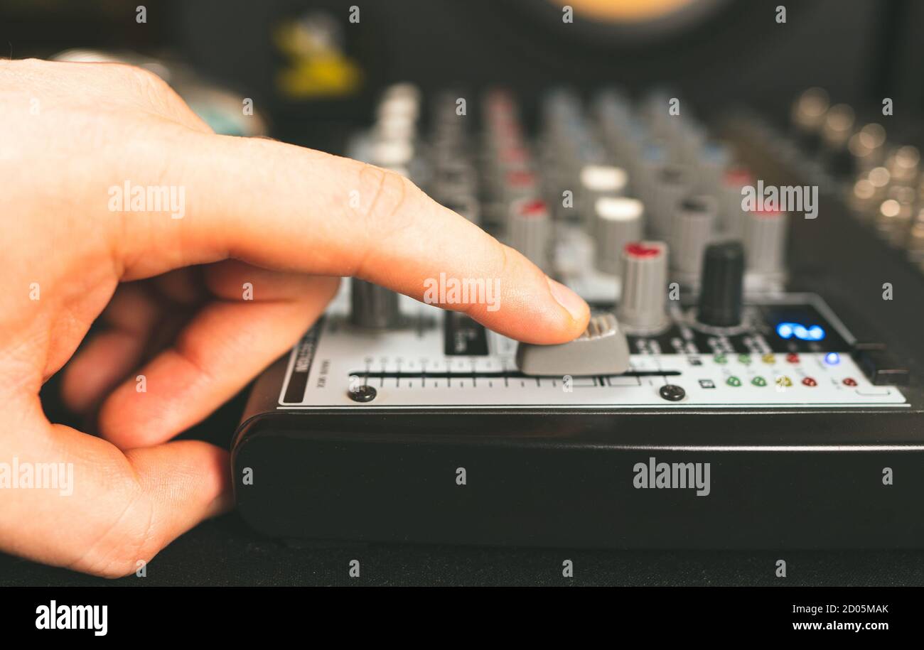Sound engineer using main control fader of studio mixer Stock Photo - Alamy