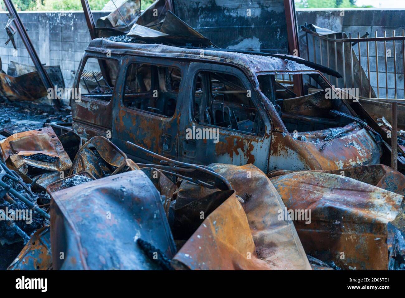 Burned out shell of minivan surrounded by scrap metal after fire Stock ...