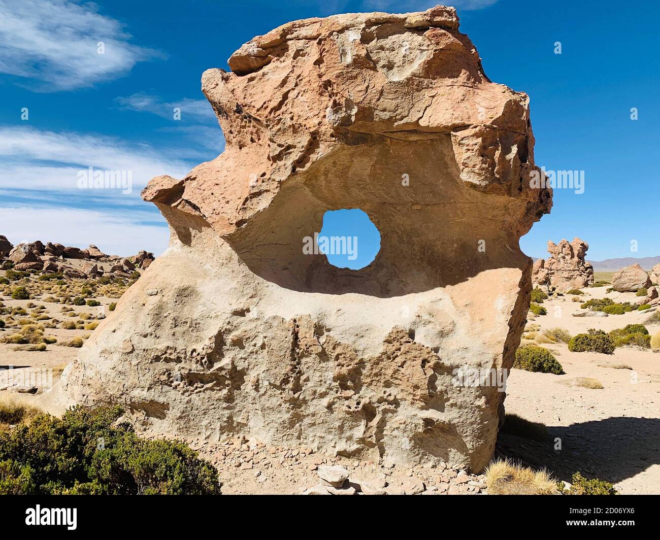 Unusual volcanic rock formation with round circle hole in dry desert ...
