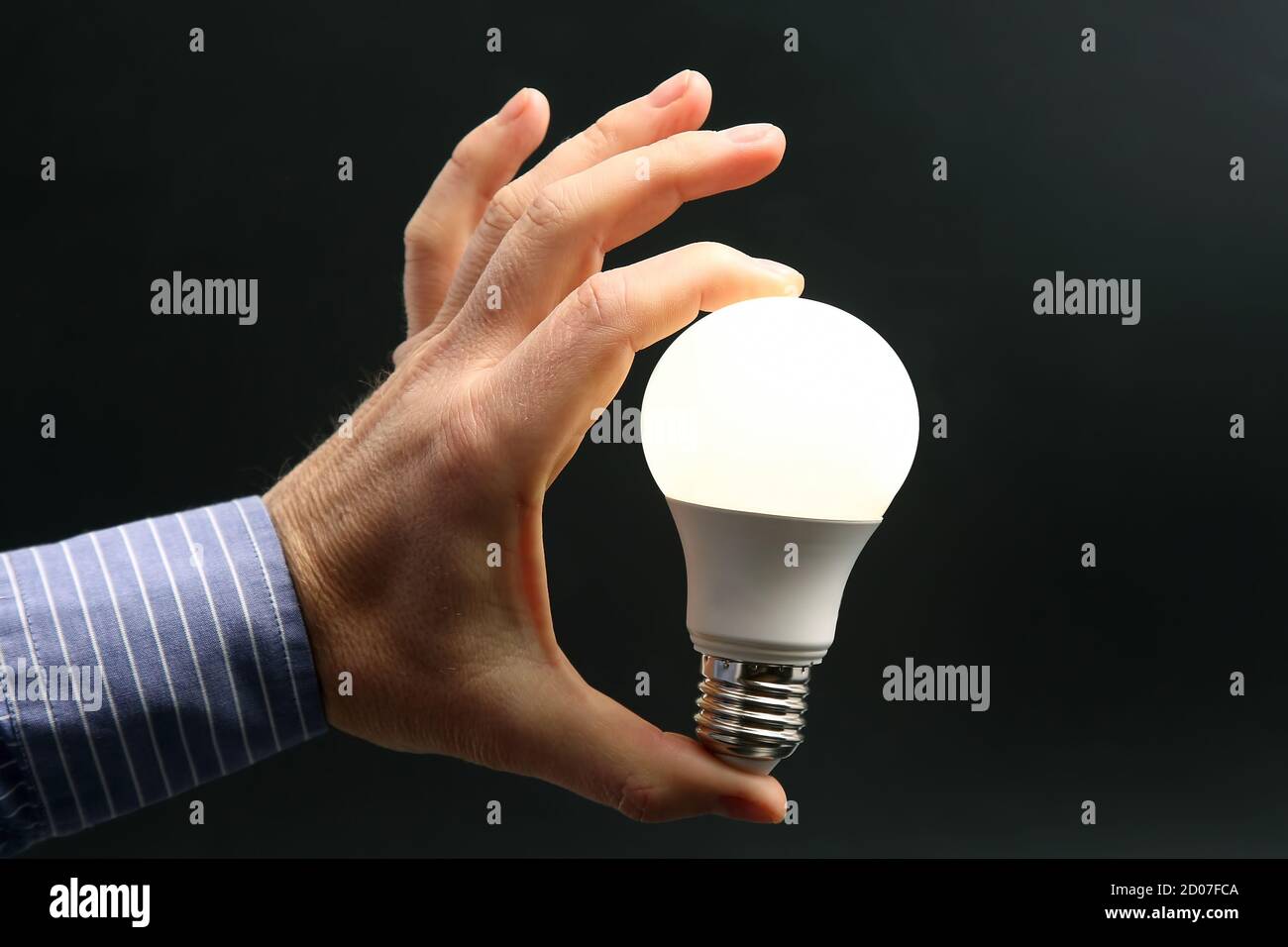 human hand holding the included led lamp on a dark background ...