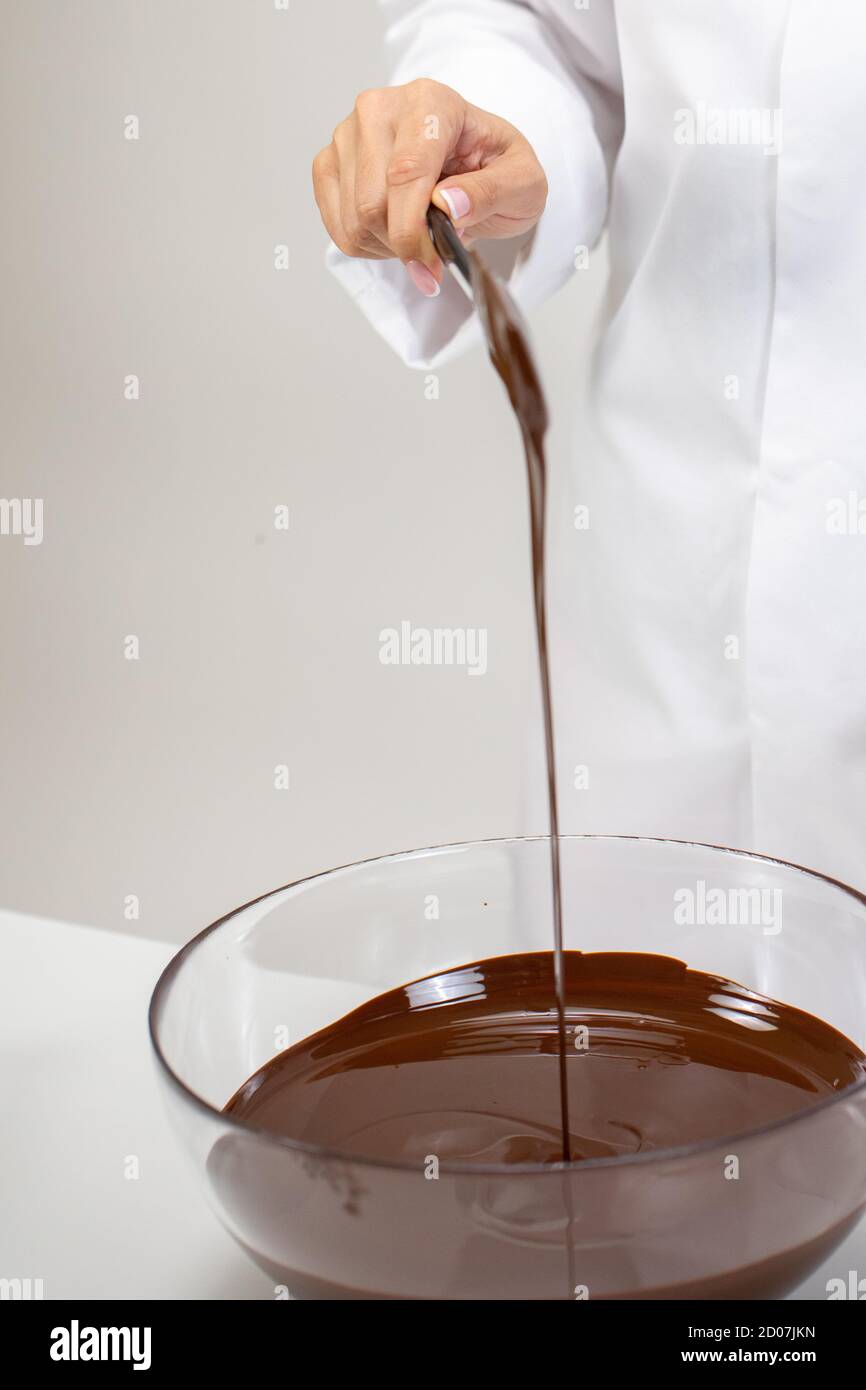Close up making organic hand-crafted chocolate, pouring dark melted ...