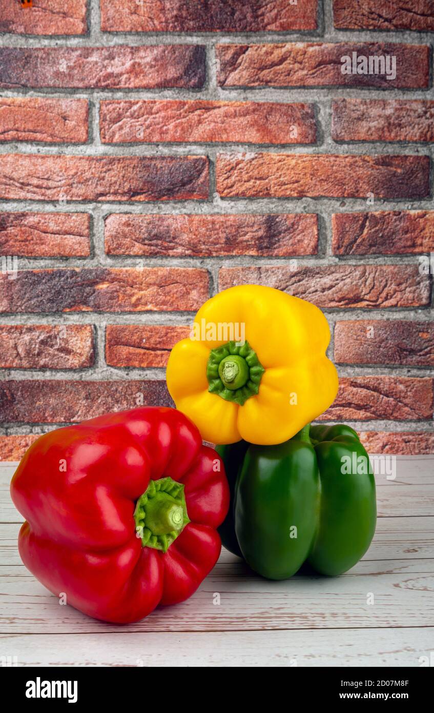 Red, green, yellow peppers whole and sliced on black stone table and ...