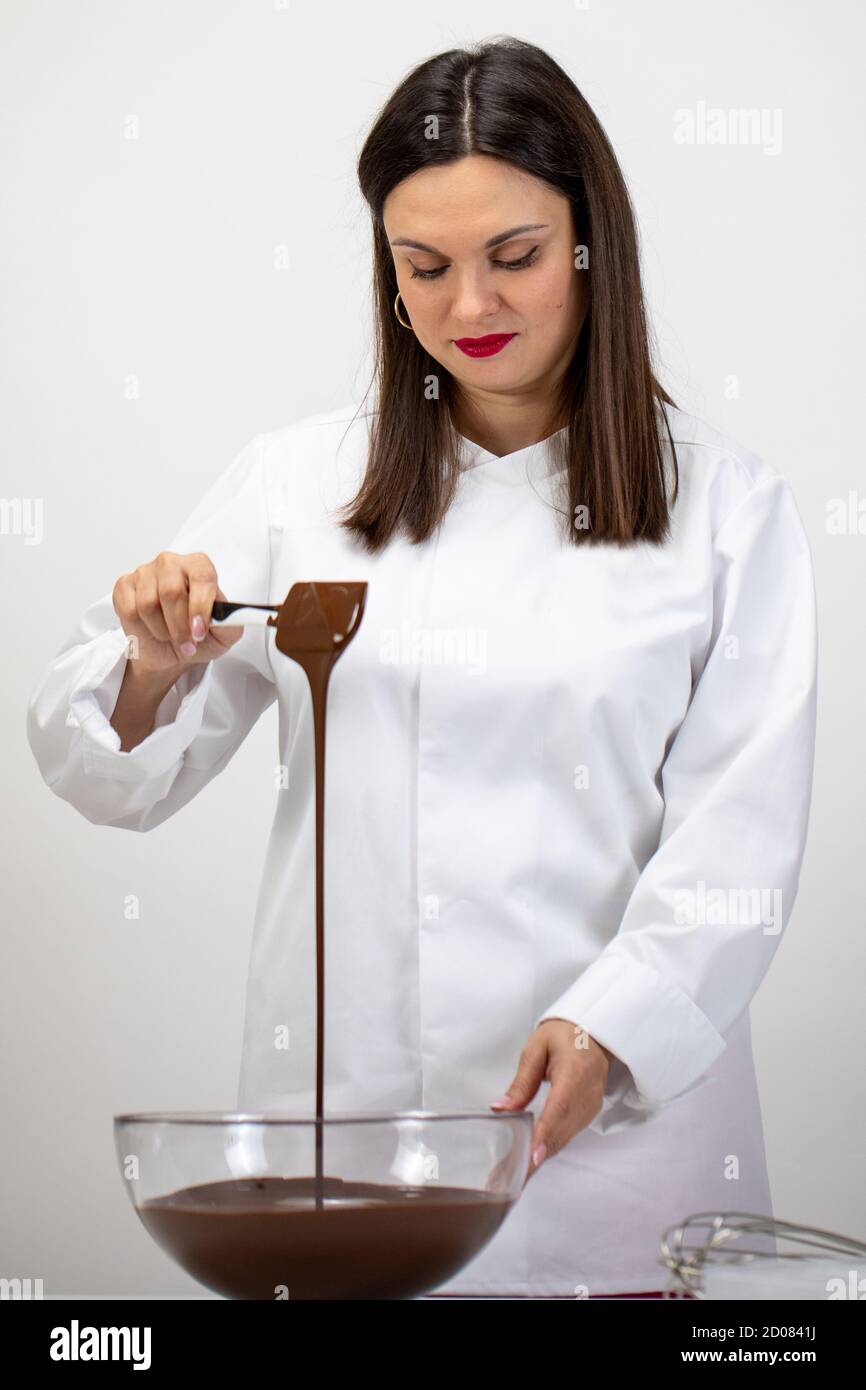 Female chef making premium hand-crafted chocolate, stirring melted ...
