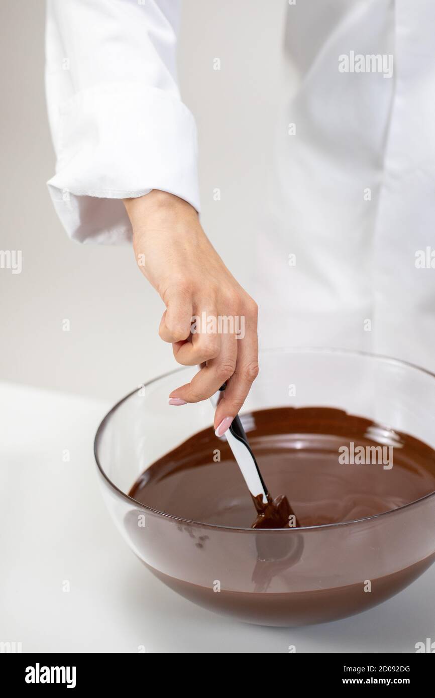 Closeup female chef stirring dark melted chocolate isolated on white ...