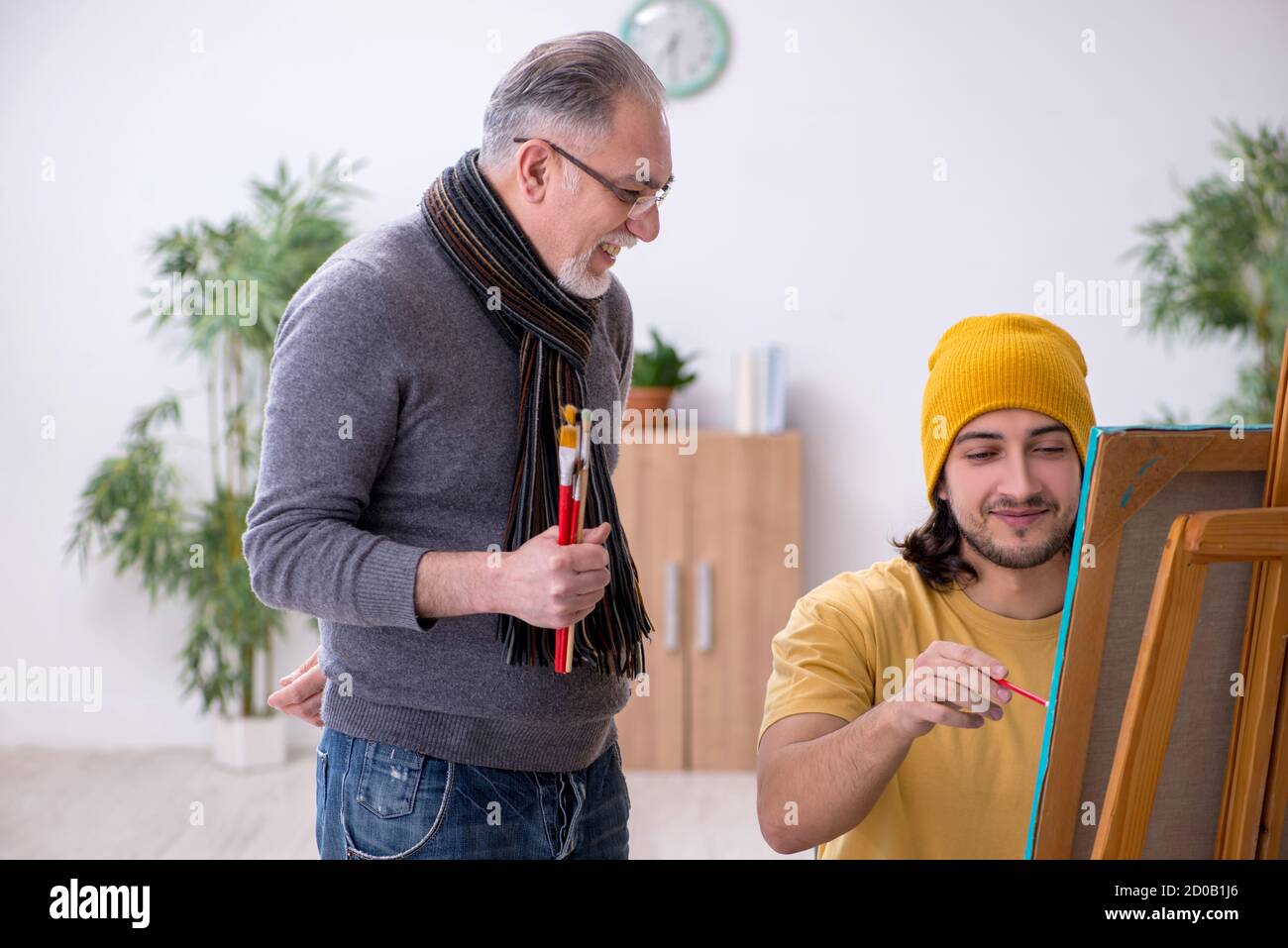 Young man taking lesson from experienced painter Stock Photo - Alamy