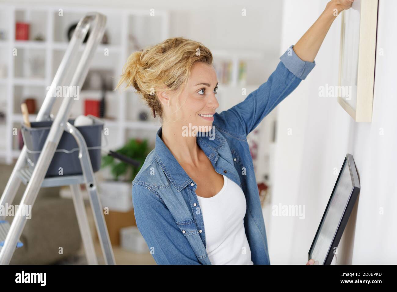 woman hanging a frame on a wall Stock Photo - Alamy