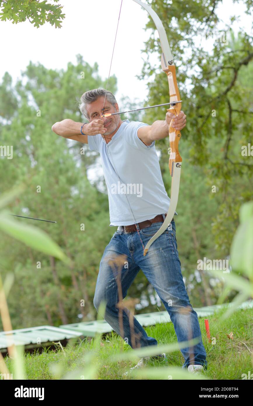 archery man shooting arrow with bow in the nature Stock Photo - Alamy
