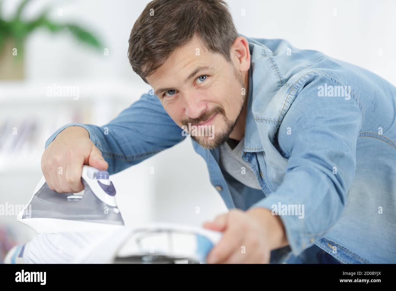 man ironing shirt on ironing board with steaming blue iron Stock Photo ...
