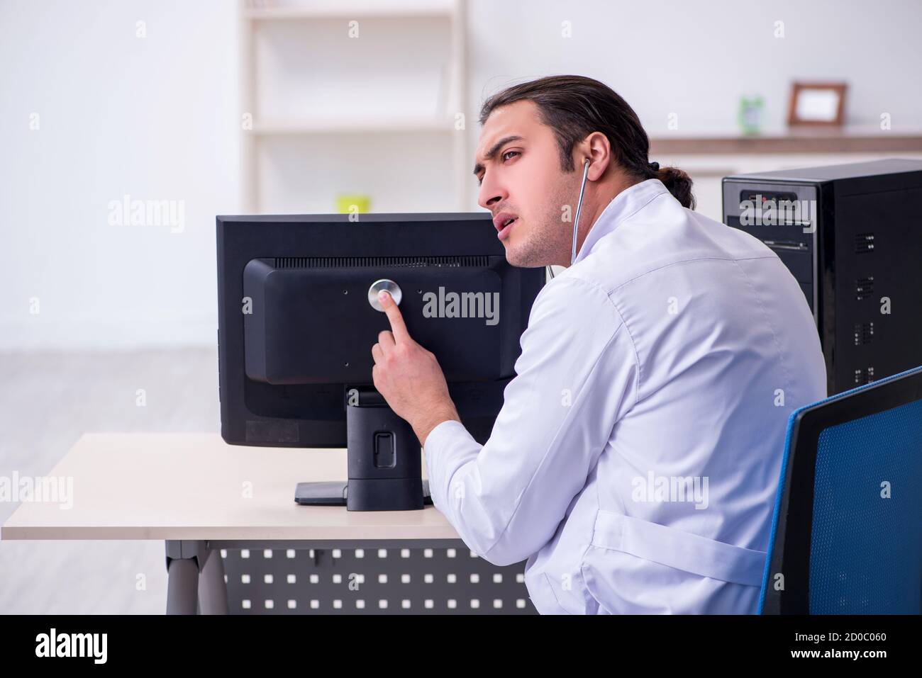 Young doctor with stethoscope repairing computer Stock Photo - Alamy