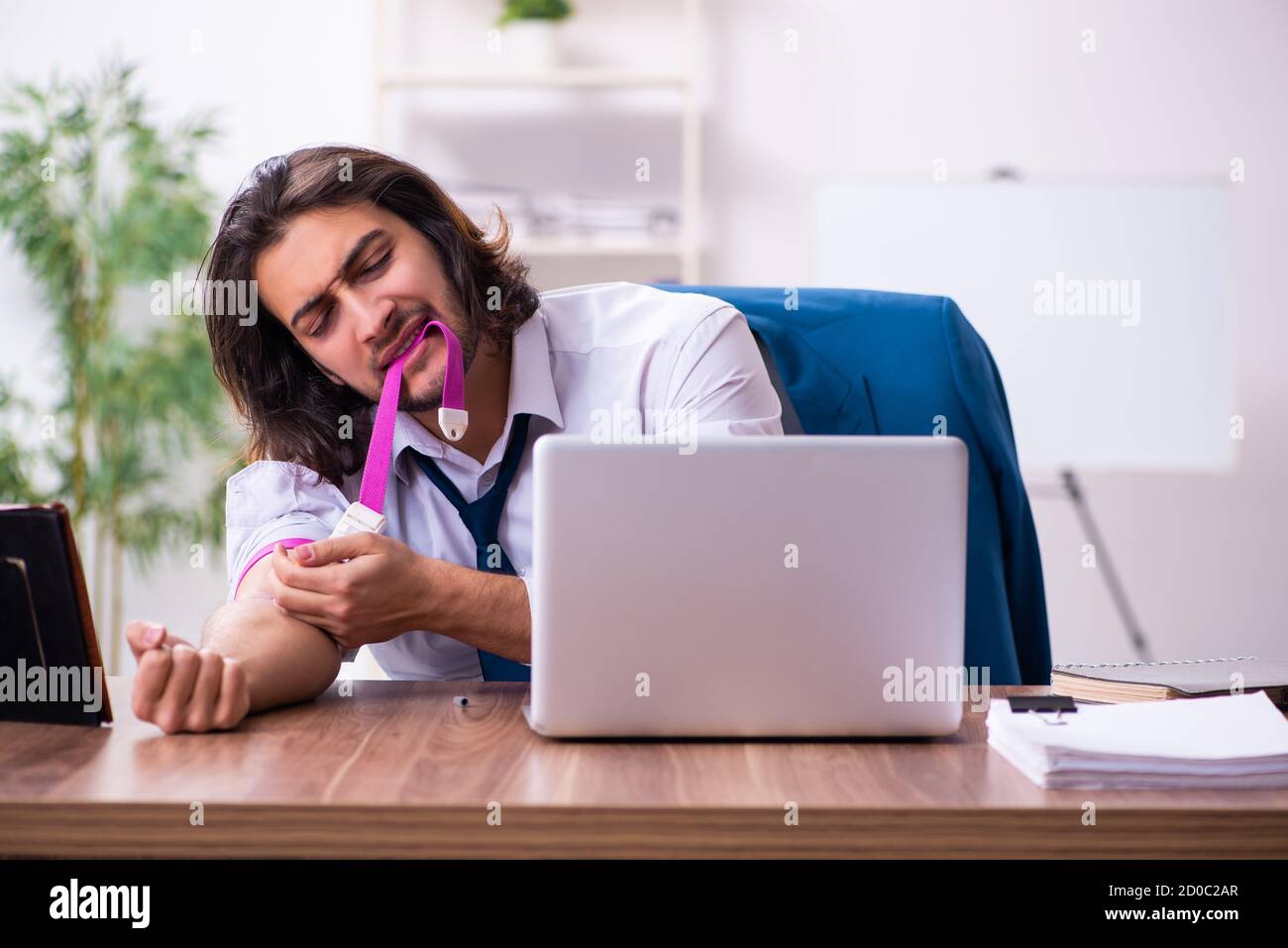 Drug addicted employee working in the office Stock Photo - Alamy