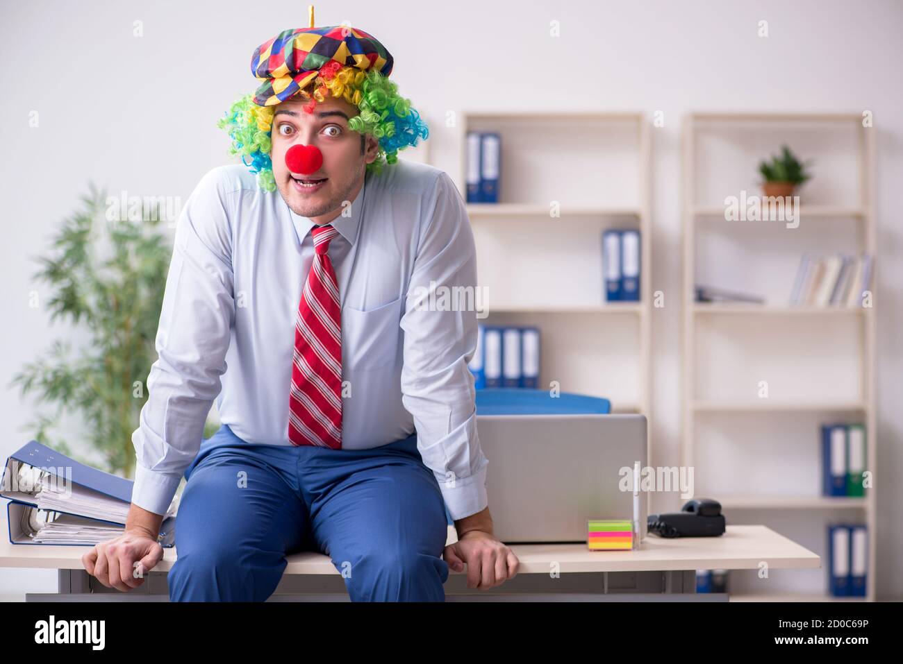 Funny employee clown working in the office room Stock Photo - Alamy