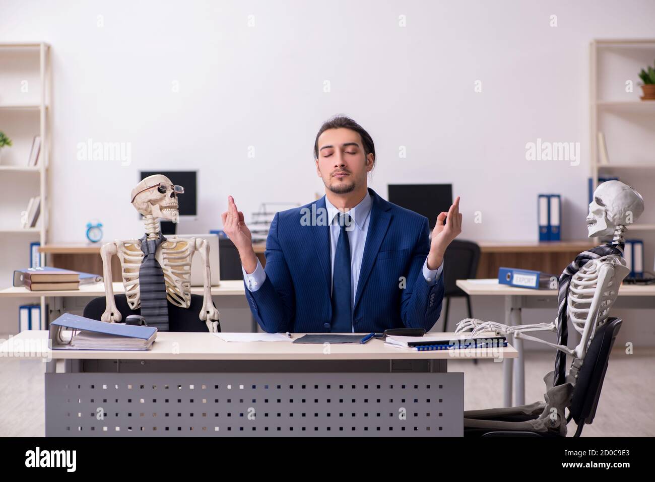 Young employee with skeletons in the office Stock Photo - Alamy