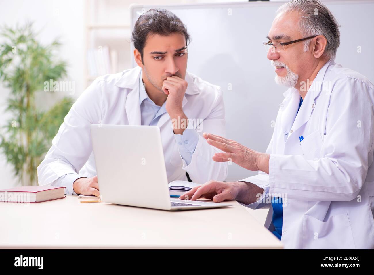 Experienced doctor teaching young assistant using computer Stock Photo ...