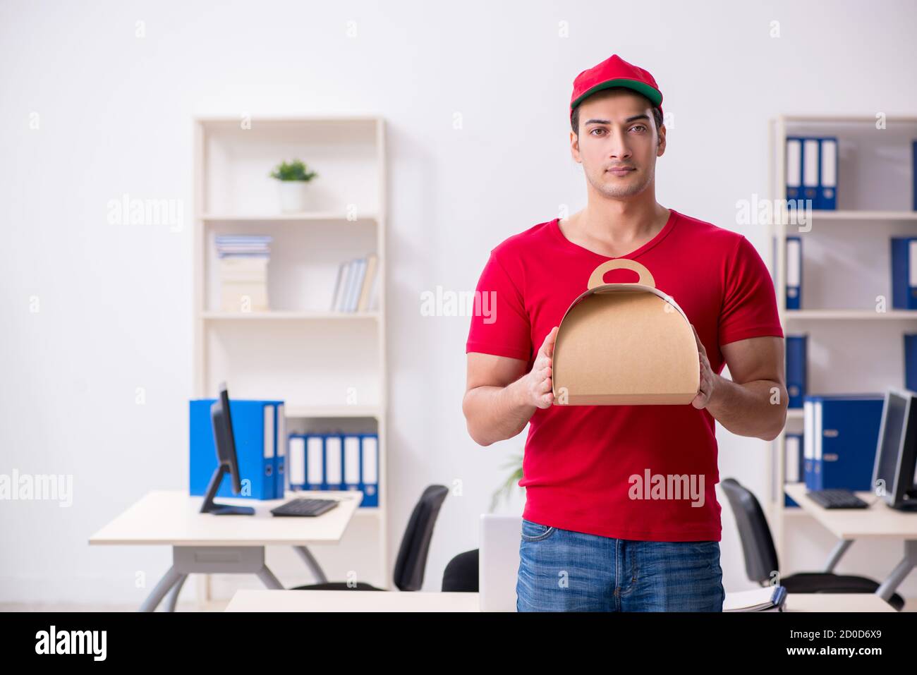 Young courier delivering cake to the office Stock Photo - Alamy
