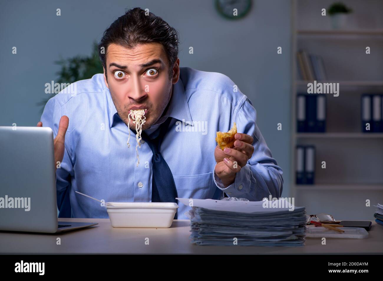 Hungry employee working late in office Stock Photo - Alamy