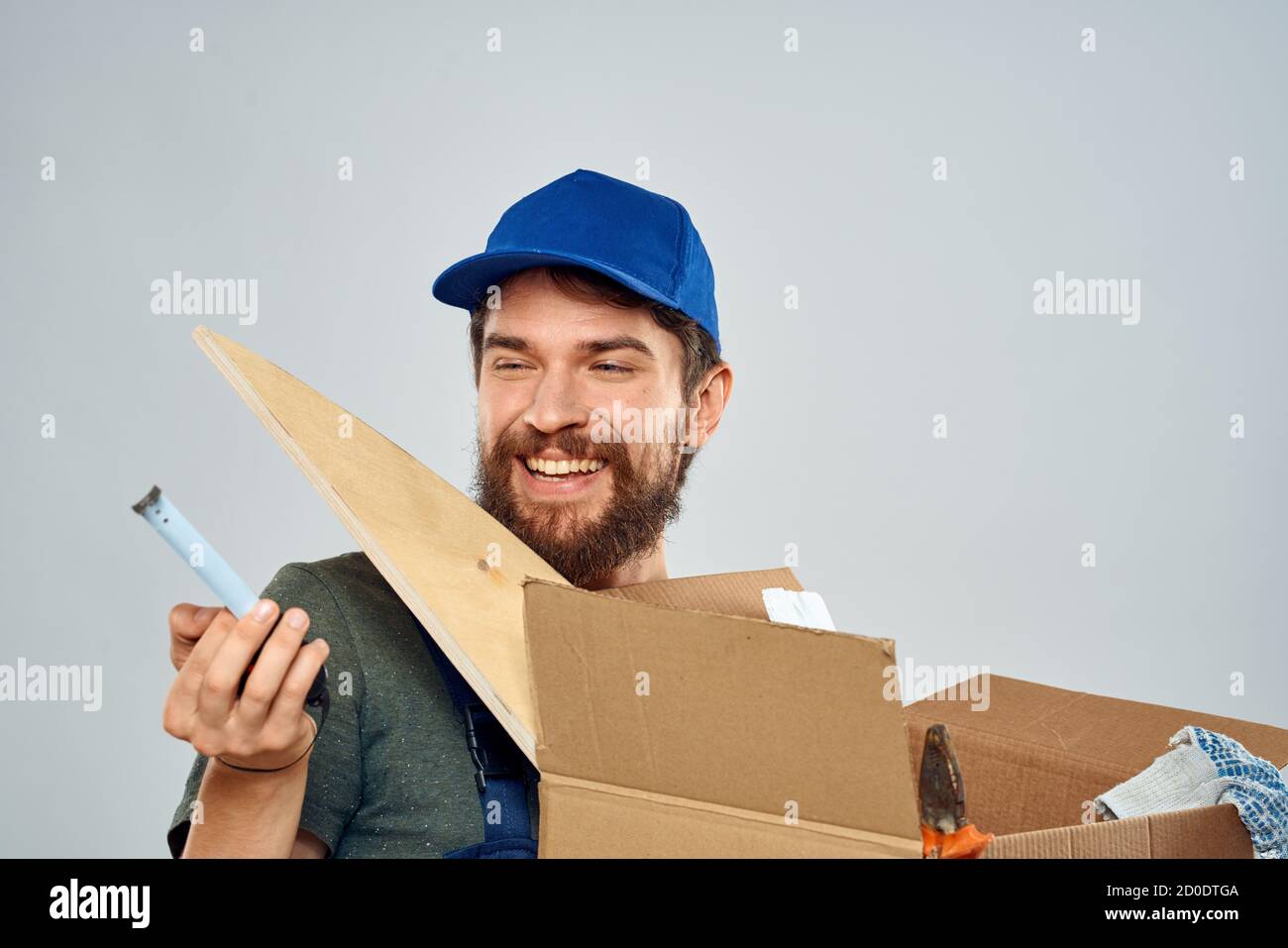 man in work uniform with box in hands tools lifestyle light background ...