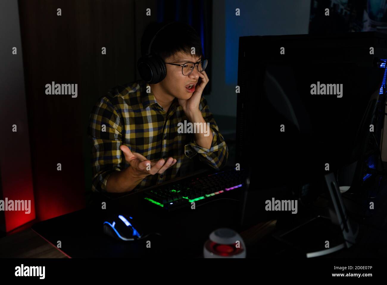 Asian man gamer in headphones stressed with hand feel depressed or ...