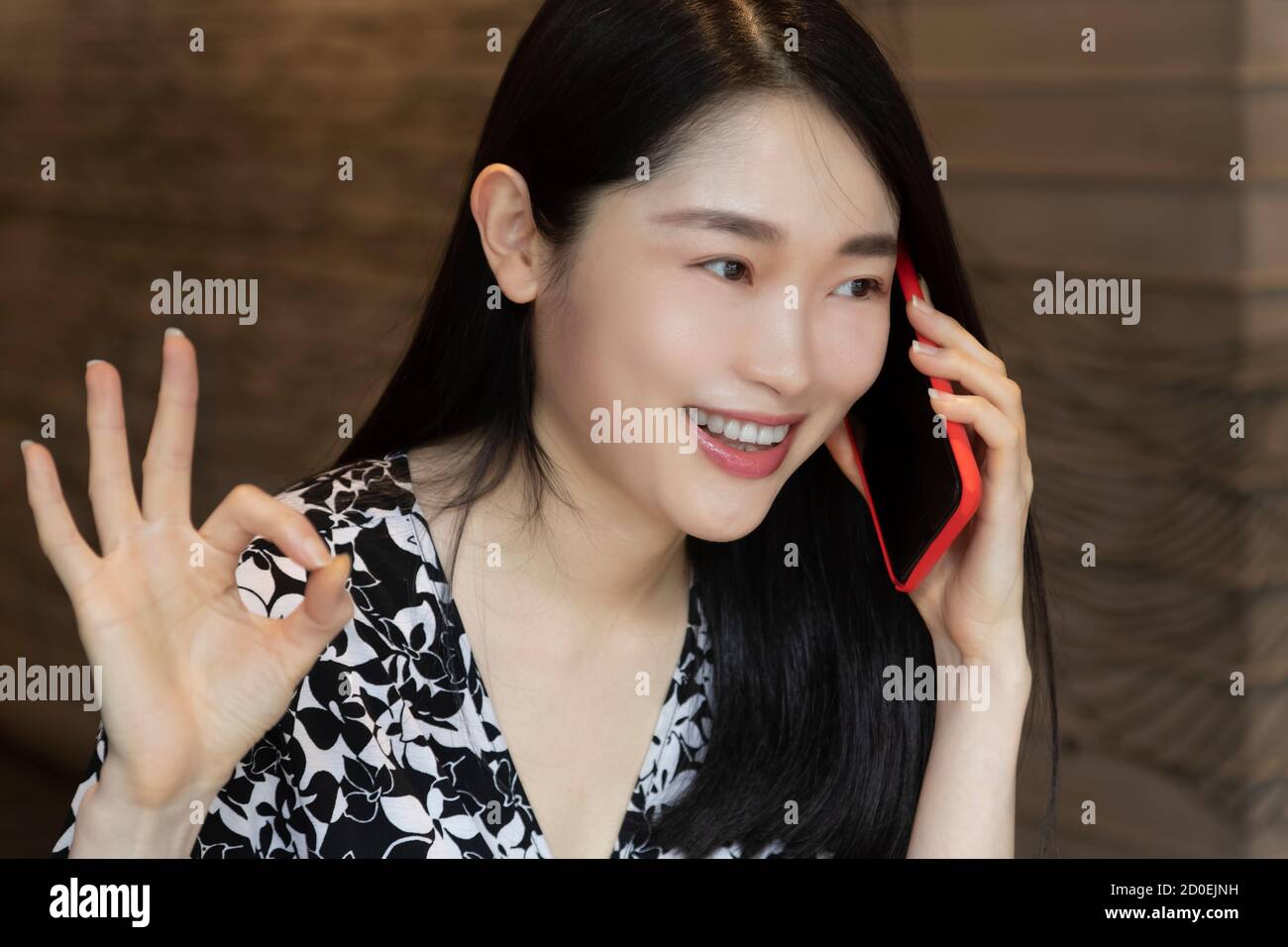 Very happy Chinese American woman using an red smart phone in a coffee ...