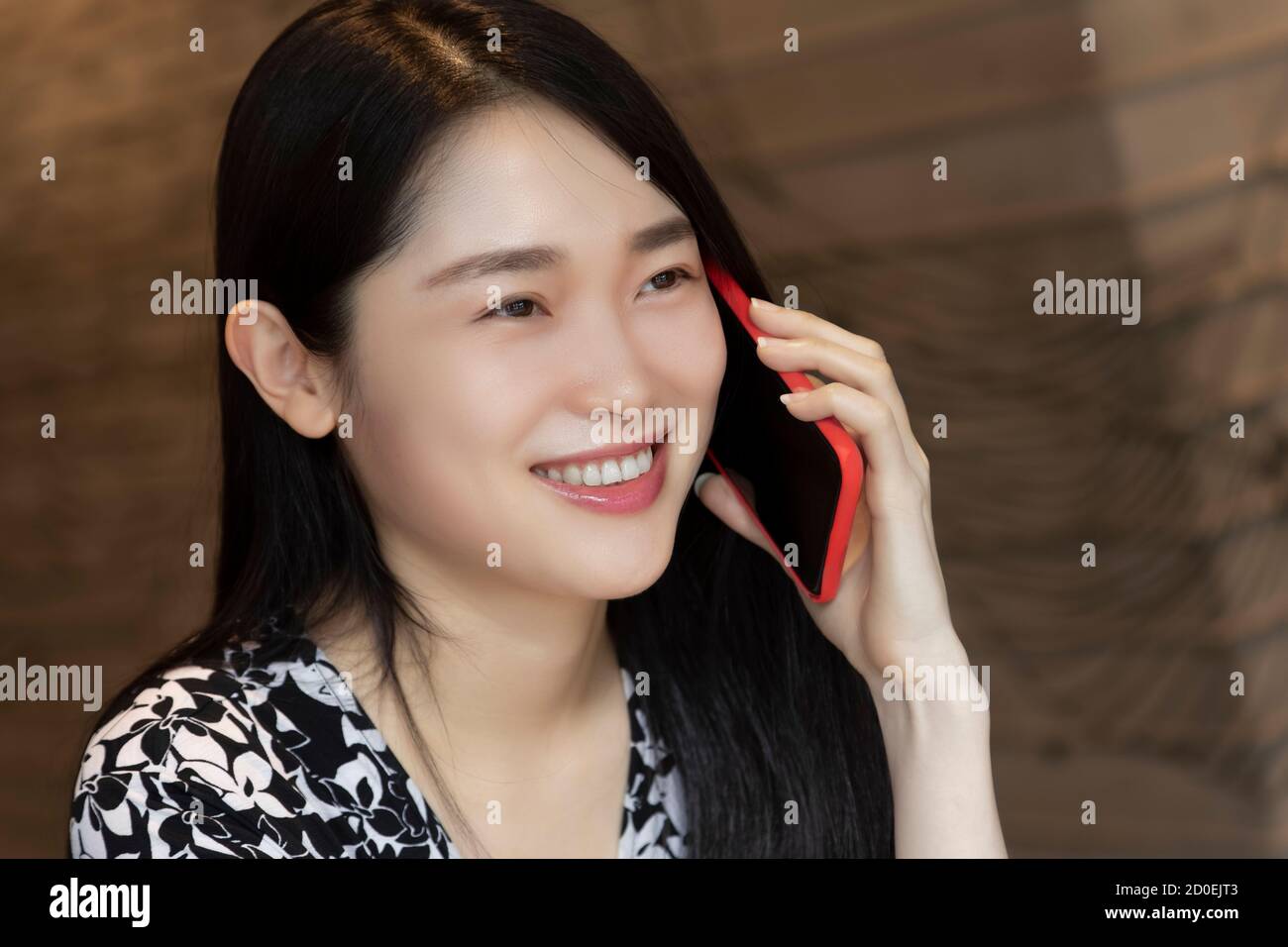 Very happy Chinese American woman using an red smart phone in a coffee ...