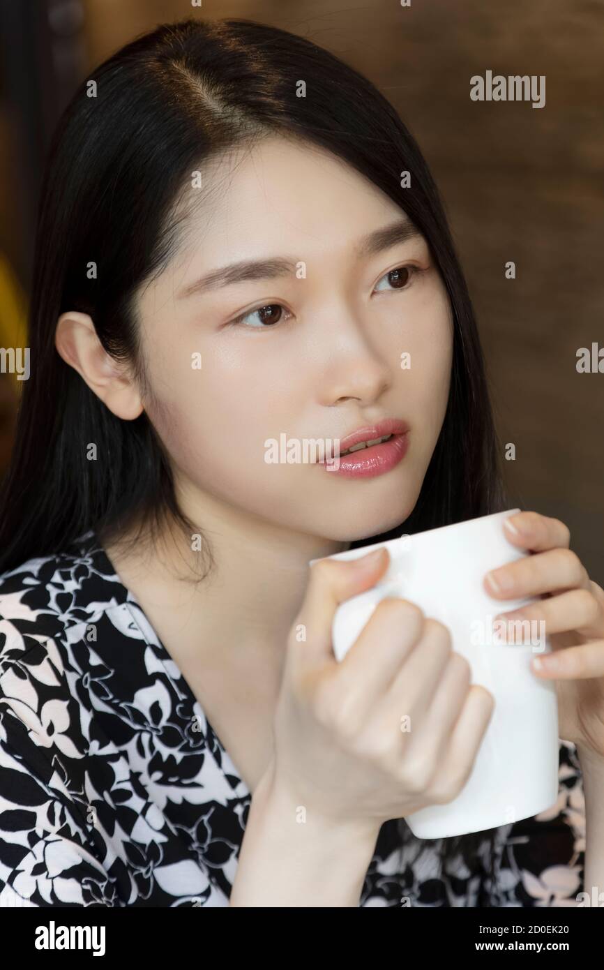 Chinese American woman holding a mug of coffee in a coffee shop with ...