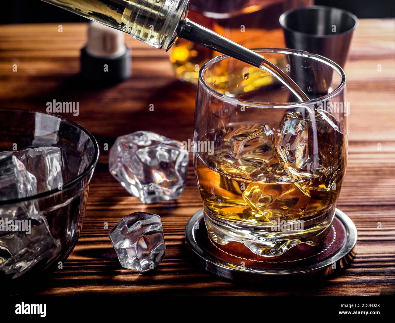 Pouring whisky in a tumbler with ice cubes - whisky on the rocks Stock ...