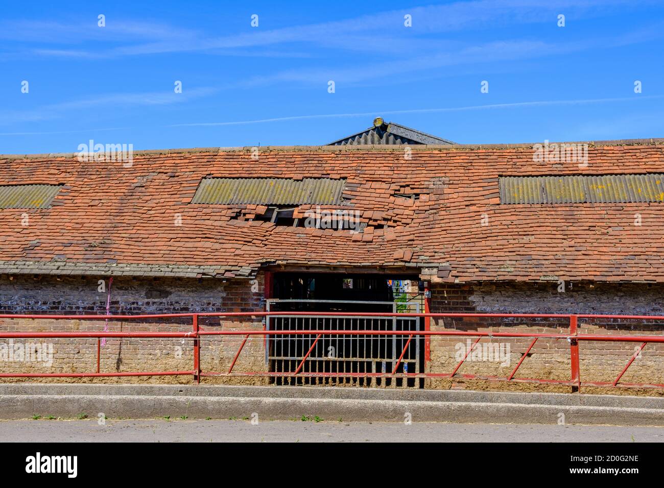 Old dilapidated farm building with broken red tiled roof with holes ...