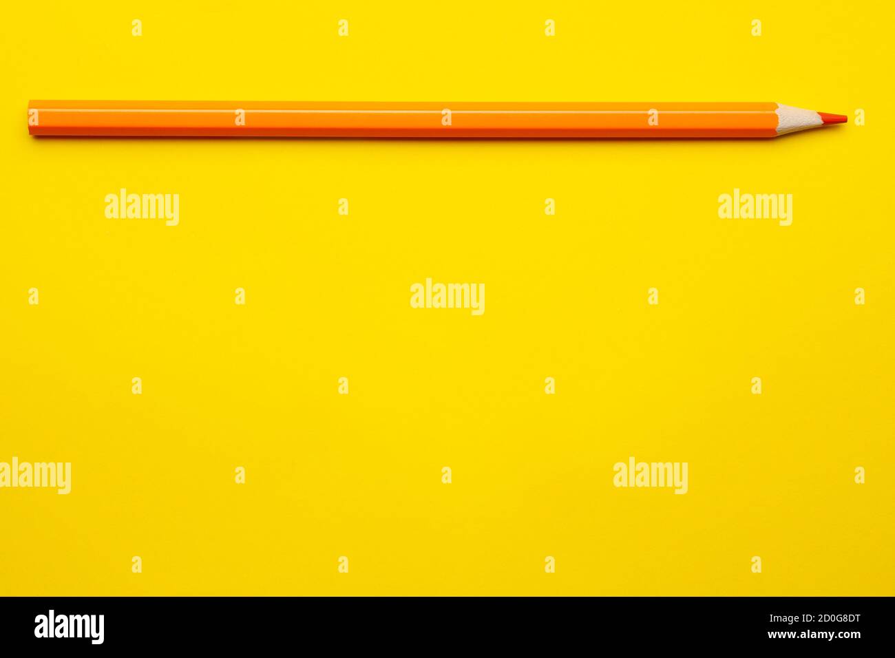 horizontal orange sharp wooden pencil on a bright yellow background ...