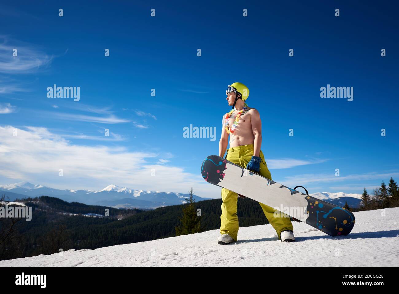 Young athletic snowboarder man in pants, helmet and boots with bare ...