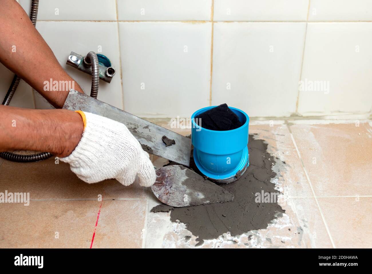 Construction workers are using plastering tools around the PVC pipe to ...