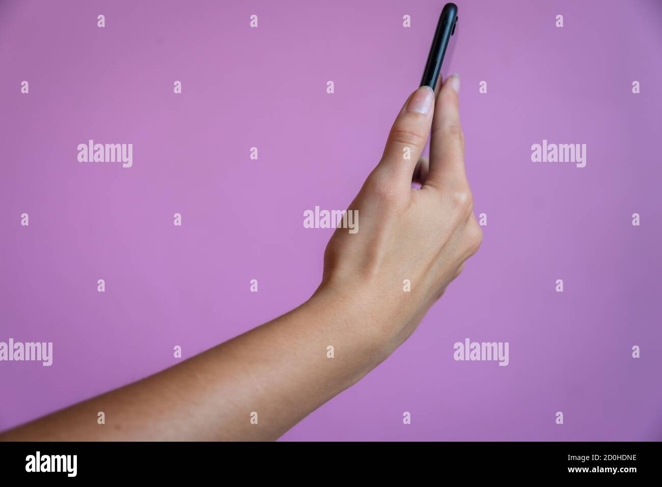 female hand holding mobile phone against a pink , Mauve background ...