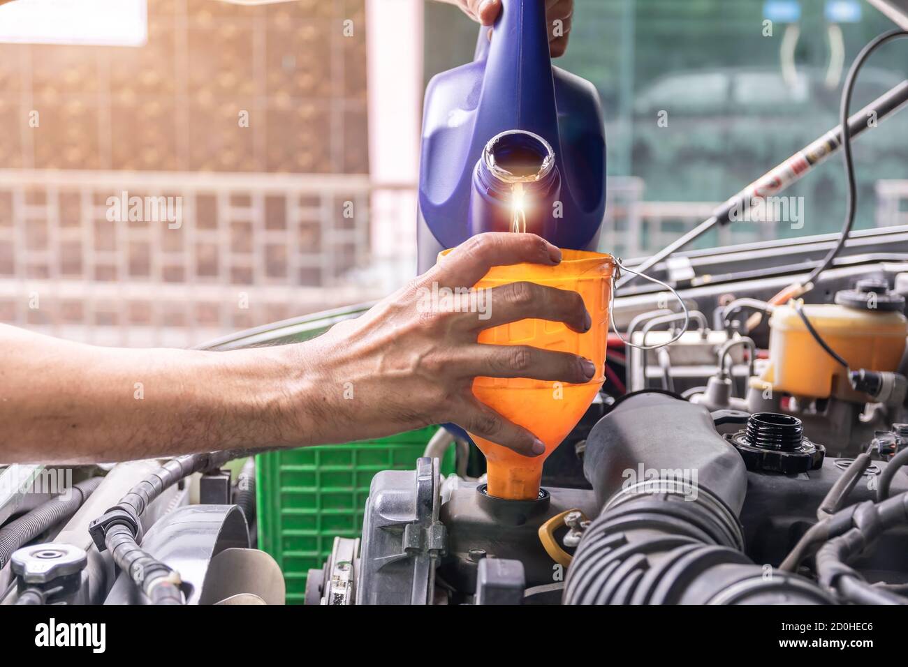 Auto mechanic is filling up the car's engine oil inside the auto repair ...
