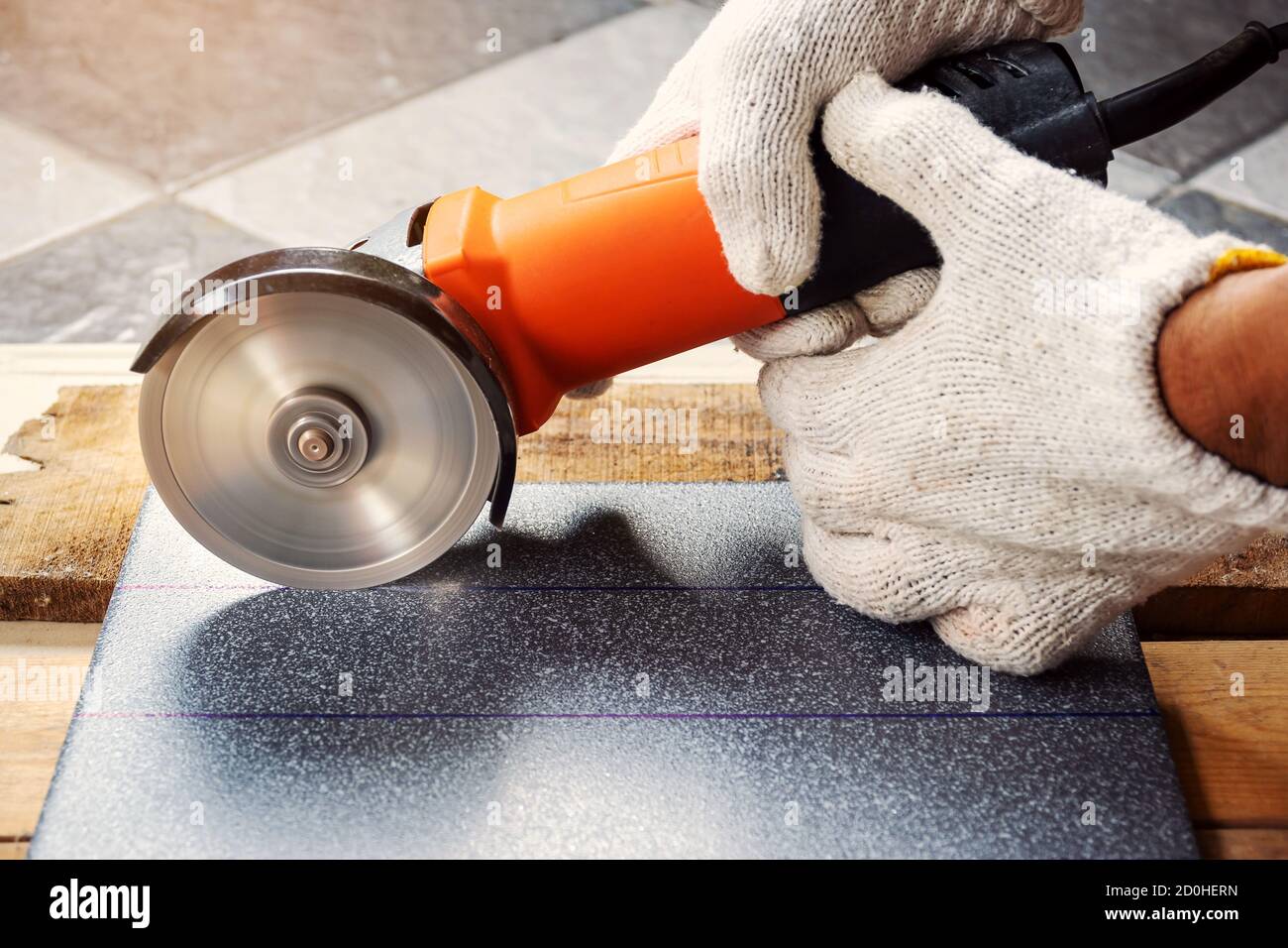 Construction worker wearing white cloth gloves was cutting the tiles ...